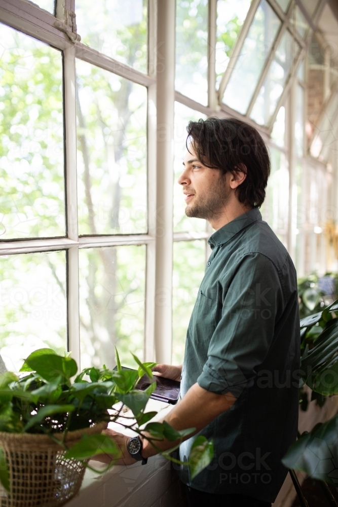 Image of Man looking through paned glass windows in creative studio ...