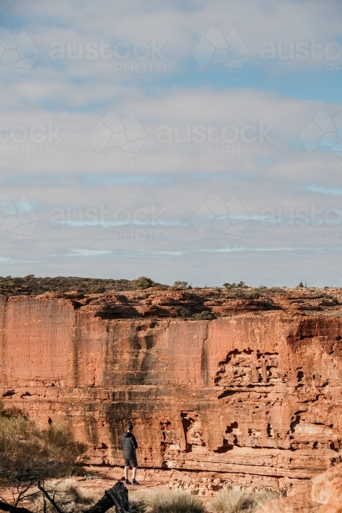 Image of Man looking towards cliff face in the outback. - Austockphoto