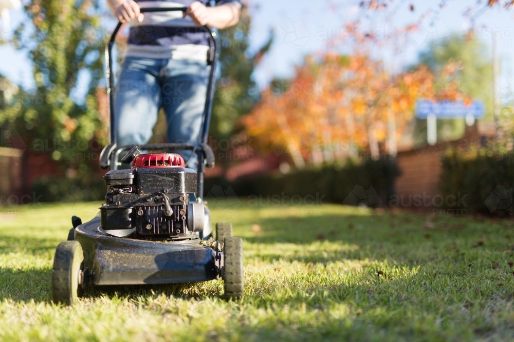 Image of man mowing the lawn in autumn - Austockphoto