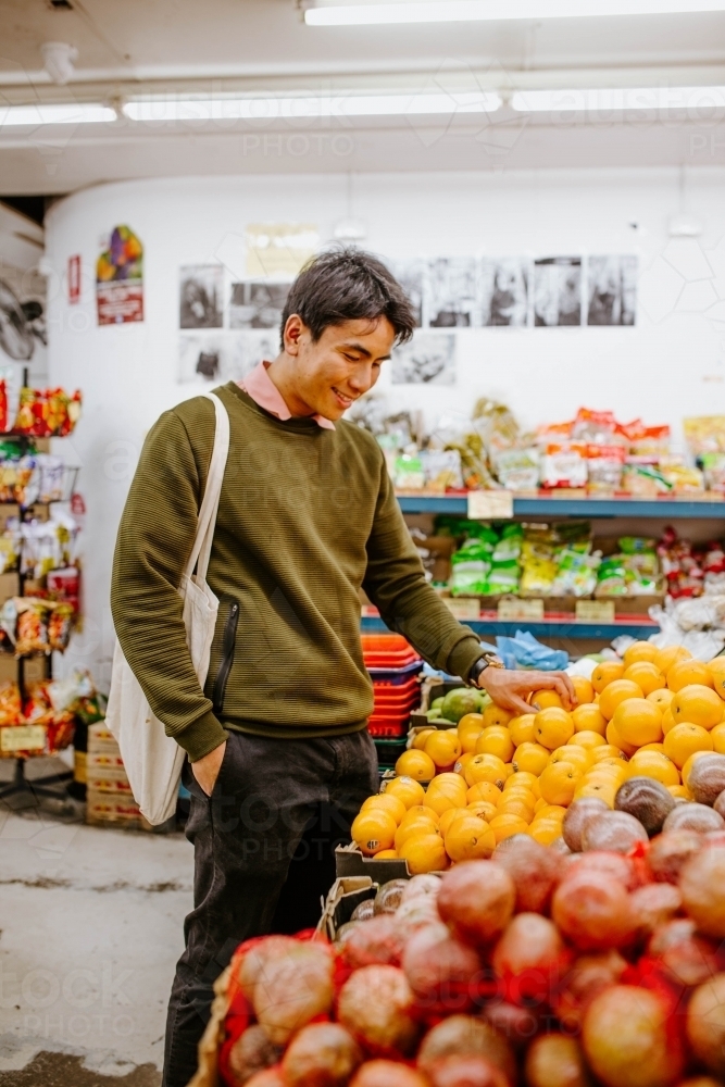 Image of Man picking fruit in fresh food supermarket - Austockphoto