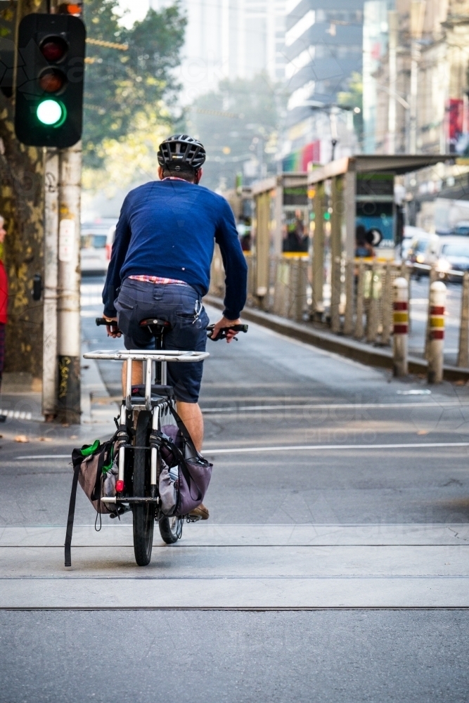 Image of Man riding bike in city traffic. - Austockphoto