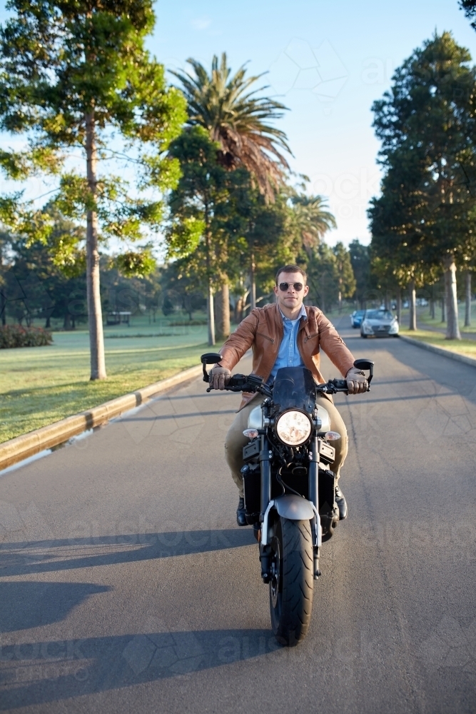 Image of Man riding motorbike on road at parklands - Austockphoto