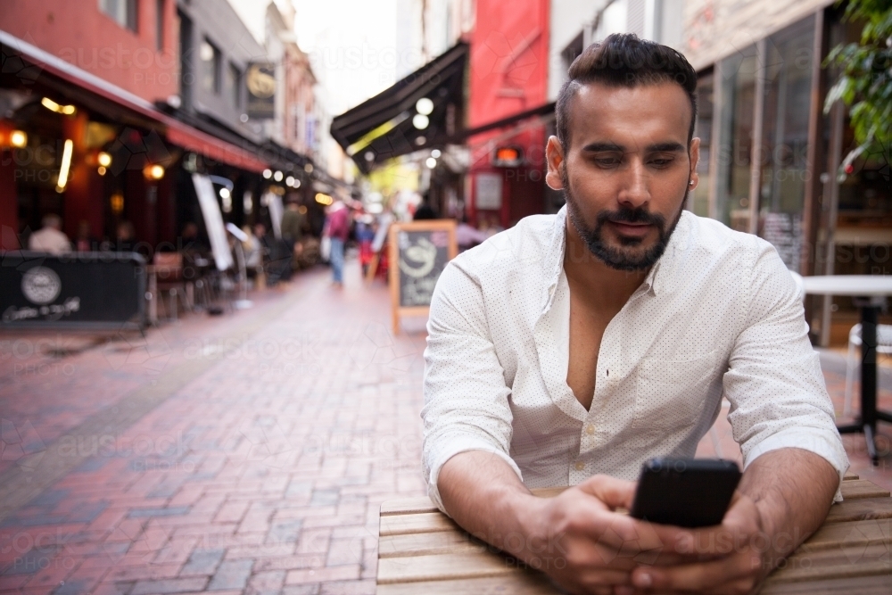Image of Man Sitting and Texting in Hardware Lane - Austockphoto