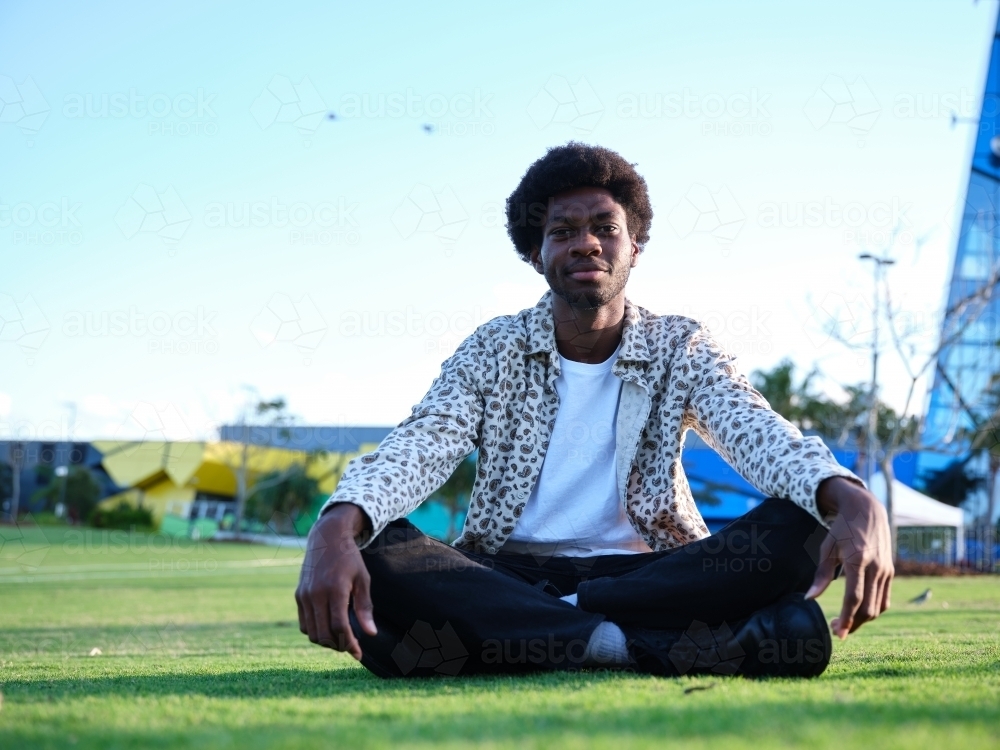 Image of Man sitting cross-legged in a park - Austockphoto