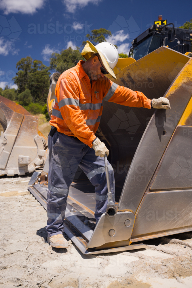 Image of Man standing inside the bucket of a payloader. - Austockphoto