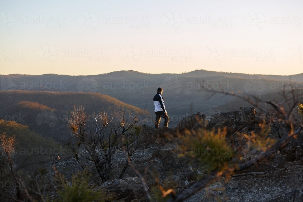 Image of Man standing looking out over mountains on sunset - Austockphoto