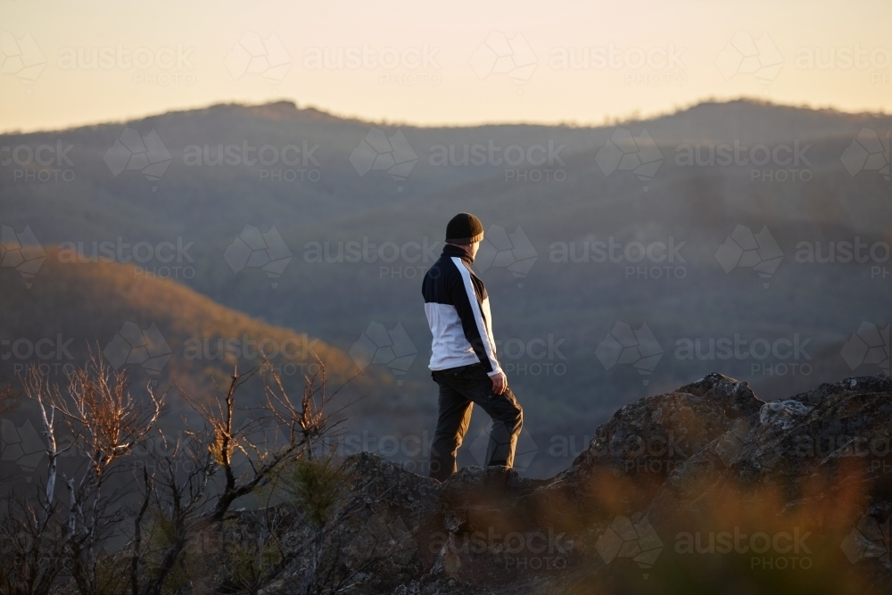 Image of Man standing looking out over mountains on sunset - Austockphoto