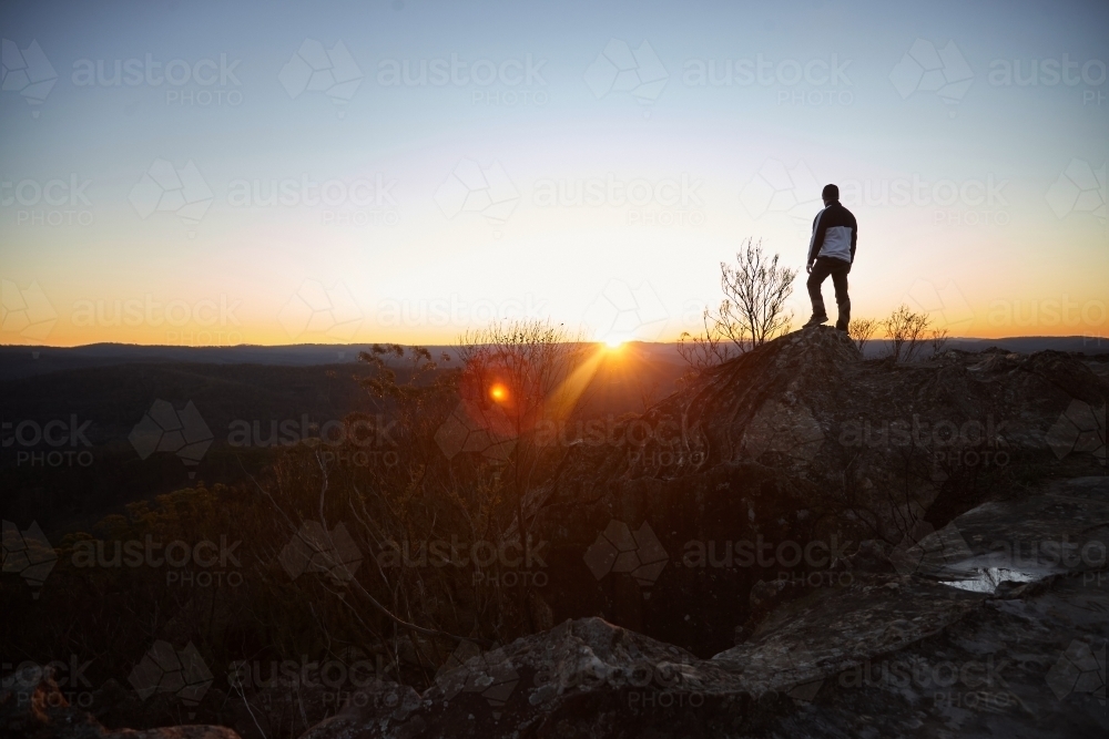 Image of Man standing looking out over mountains on sunset - Austockphoto