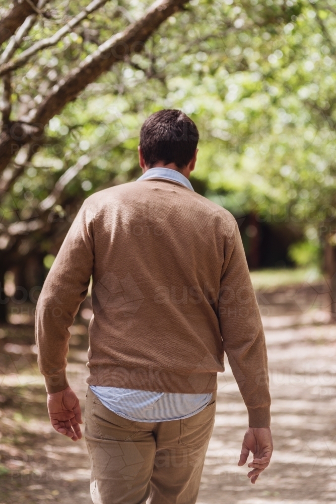 Image of man walking down a treelined path - Austockphoto