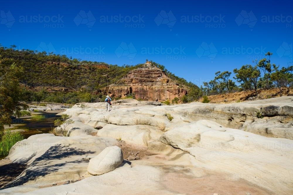 Image of Man walking in a gorge landscape towards rock formation ...