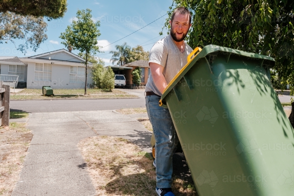 Image of Man with Down Syndrome Bringing In Wheely Bin - Austockphoto