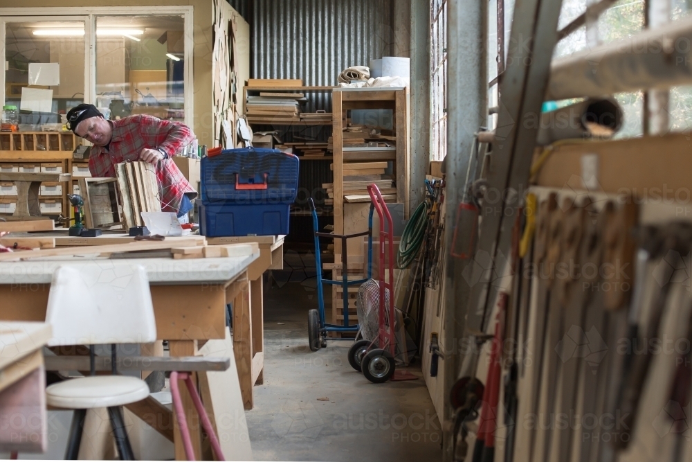 Image of Man working at a Men's shed with tools on the wall - Austockphoto