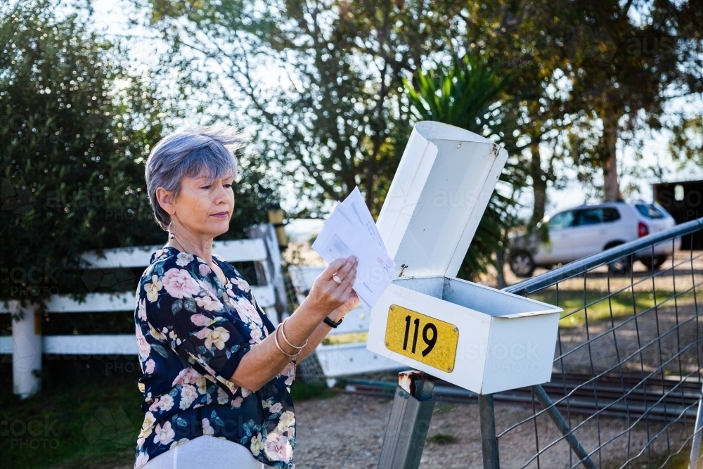 Image of Mature aged woman checking her mailbox for letters - Austockphoto