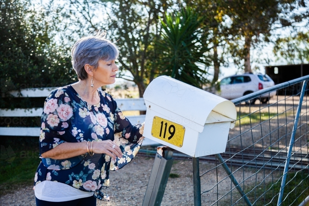 Image of Mature aged woman checking her mailbox for letters - Austockphoto