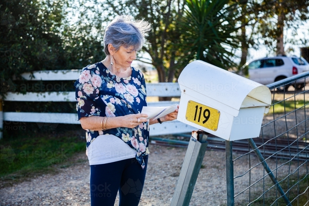 Image of Mature aged woman checking her mailbox for letters - Austockphoto