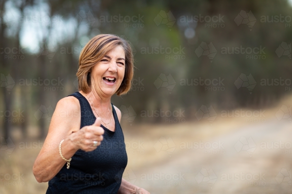 Image of mature lady laughing and gesturing outdoors - Austockphoto