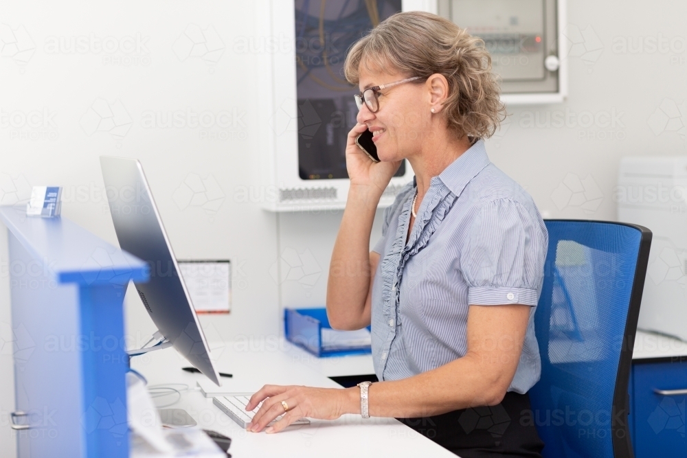 Image of Mature woman working at office desk - Austockphoto