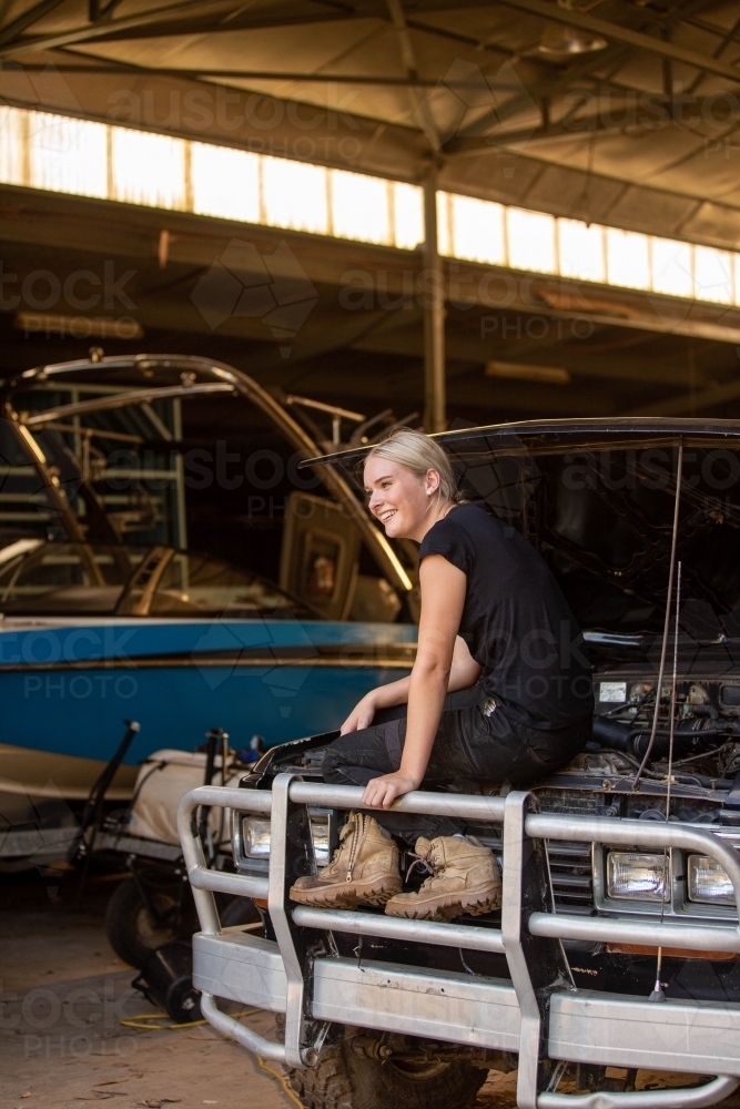 Image of Mechanic sitting on the front of a 4wd looking away - Austockphoto