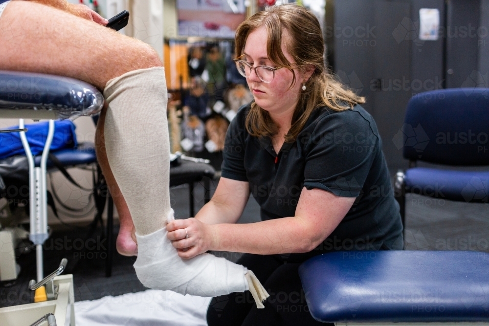 Image of medical professional putting walking cast on leg - Austockphoto