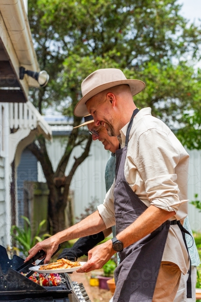 Image of men cooking lunch food on bbq in backyard of country home ...