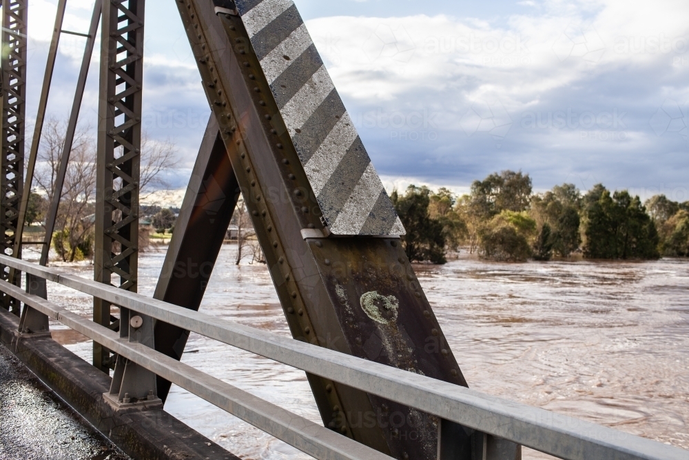 Image of metal beam of bridge with flooding Hunter River rising up ...