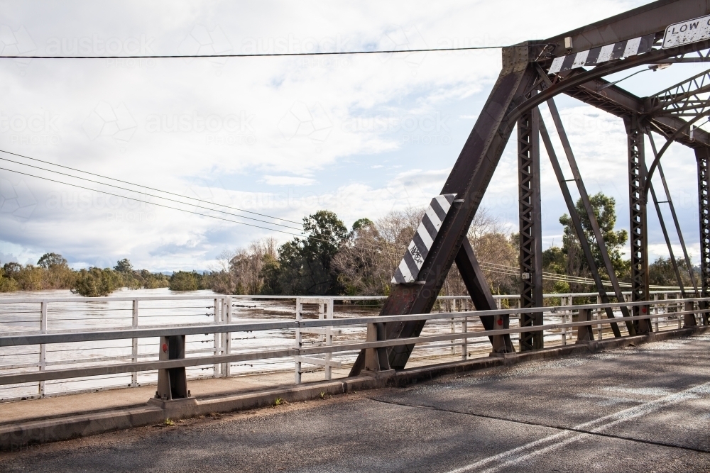 Image of metal beam of bridge with flooding Hunter River rising up ...