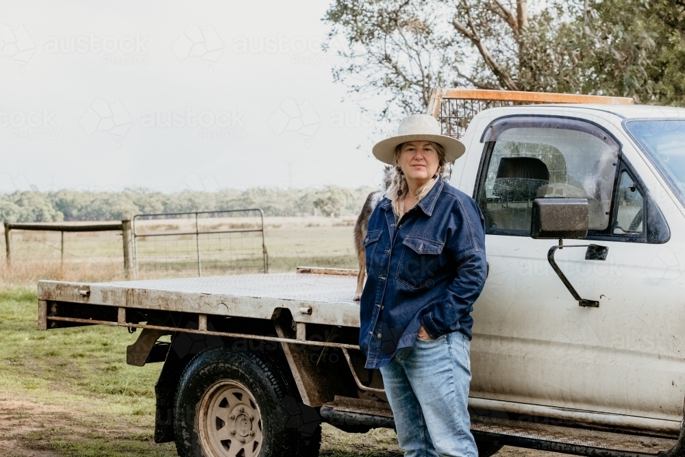 Image of Mid fifties woman standing beside farm ute. - Austockphoto