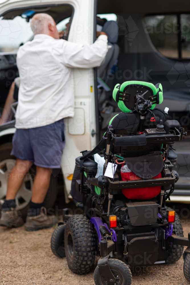 Image of Middle aged man helping his son out of the van into wheelchair ...