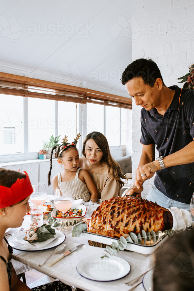 Image of Middle aged man making thin cuts of roasted ham on the table ...