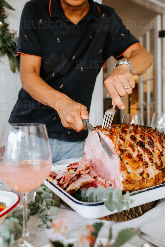Image of Middle aged man making thin cuts of roasted ham on the table ...