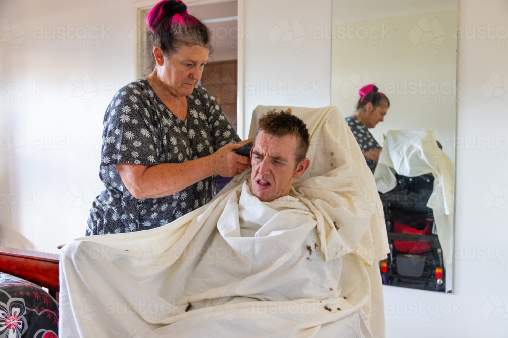 Image of Middle aged woman shaving head of her son with disability ...