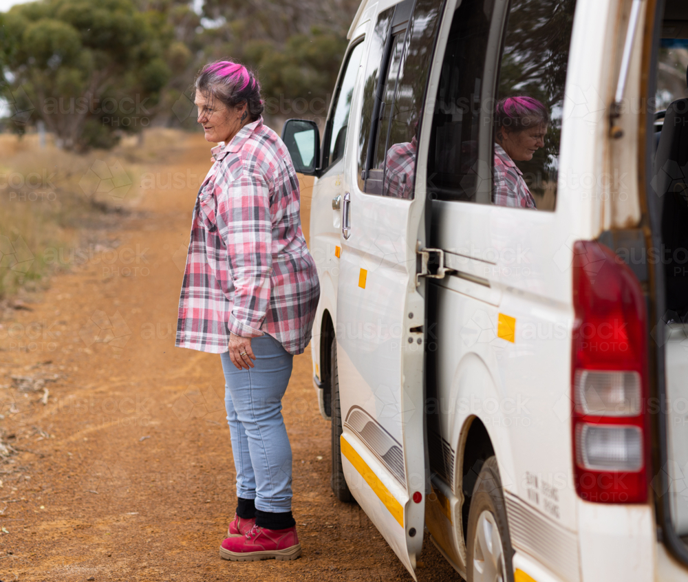Image of Middle aged woman standing beside the van on dirt road ...