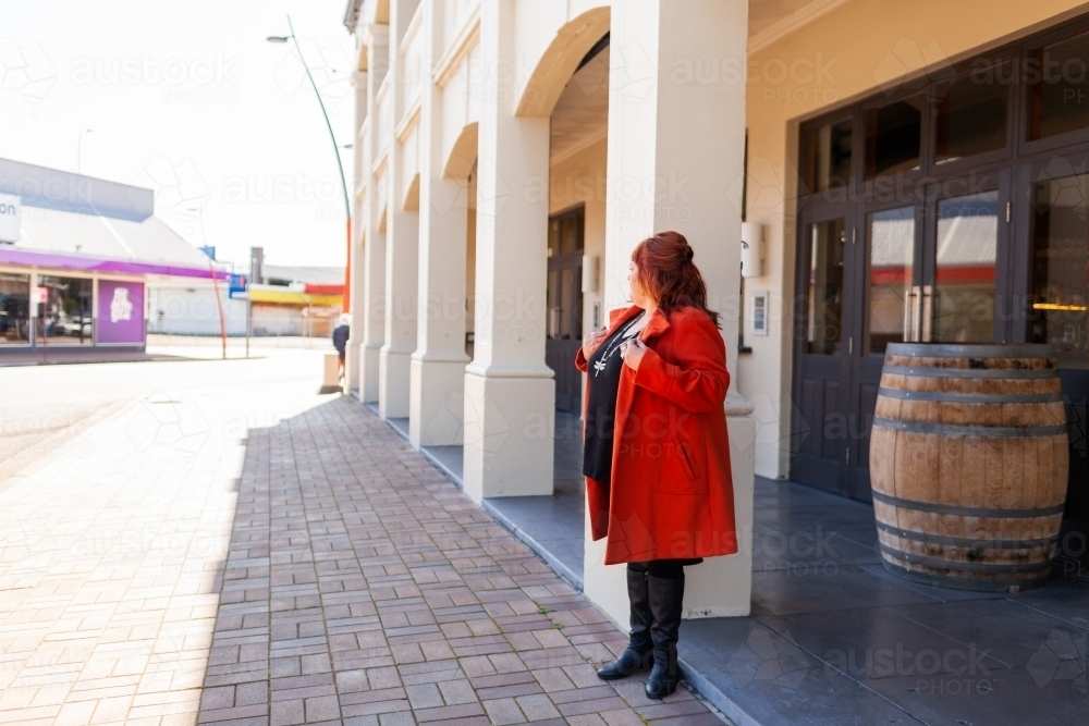 Image of Middle aged woman standing on footpath in front of pub ...