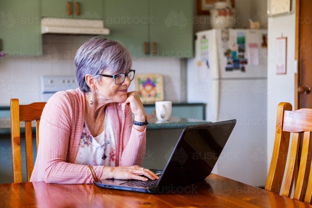 Image of Middle aged woman using online banking from her laptop ...
