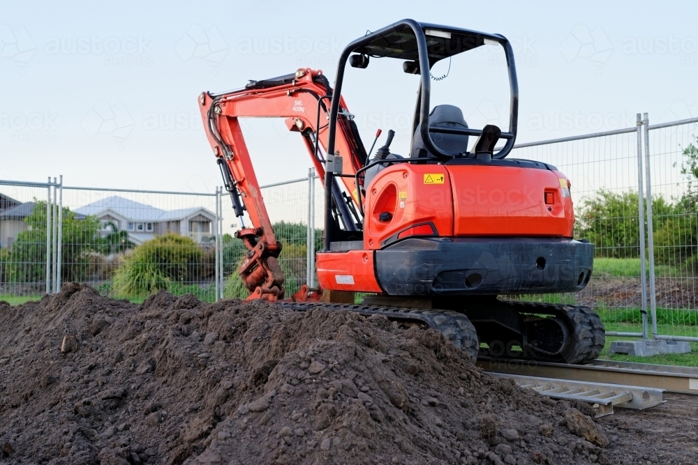 Image of Mini digger standing idle at a construction site - red ...