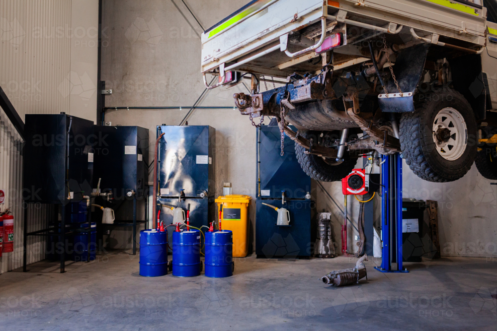 Image of Mining fleet vehicle hanging on hydraulic lift inside workshop ...