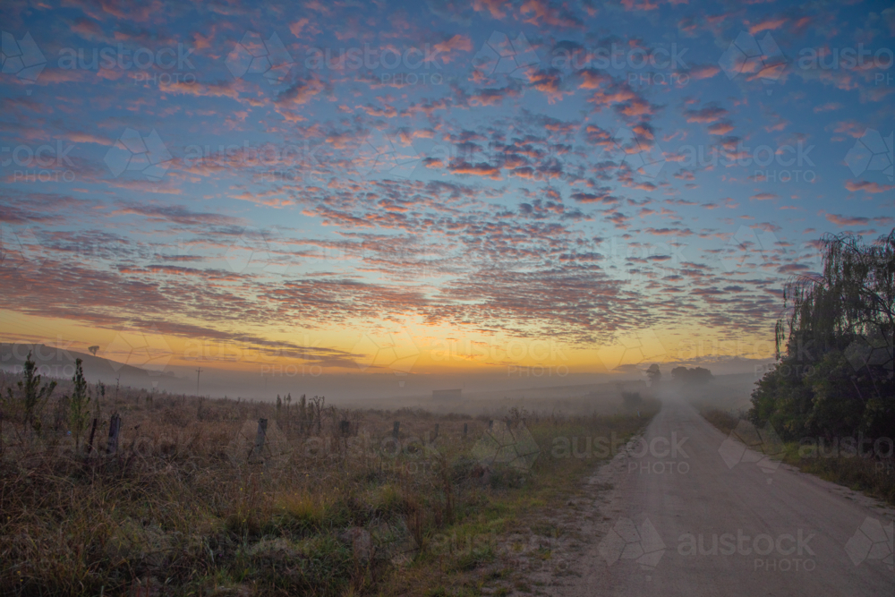 Image of Misty early morning dawn above gravel country road - Austockphoto