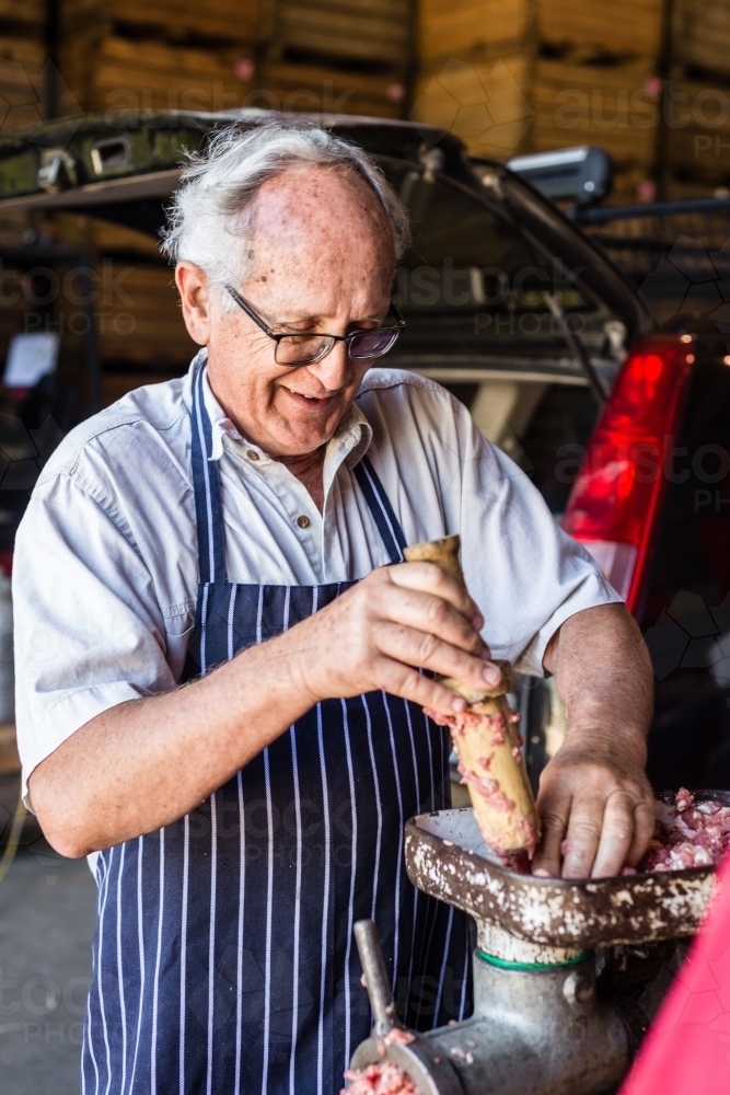 Image of mobile butcher pushing meat through mincing machine - Austockphoto