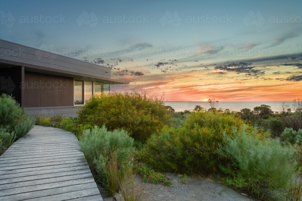 Image of modern house overlooking the ocean at sunset - Austockphoto