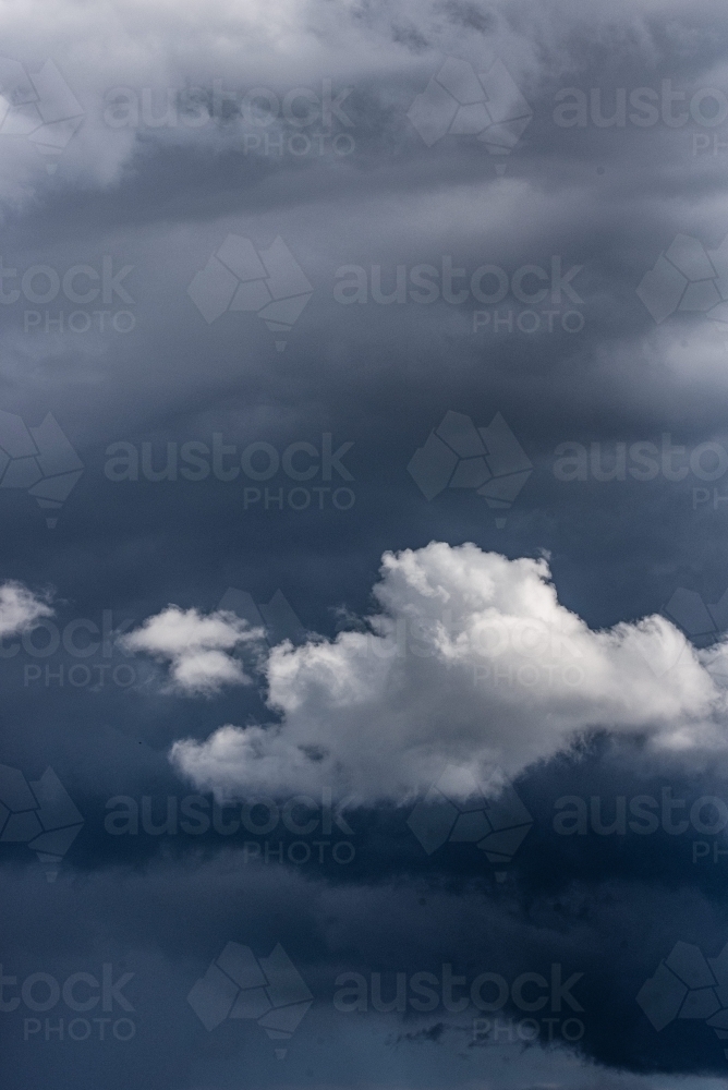 Image of Moody clouds with one white cloud - Austockphoto