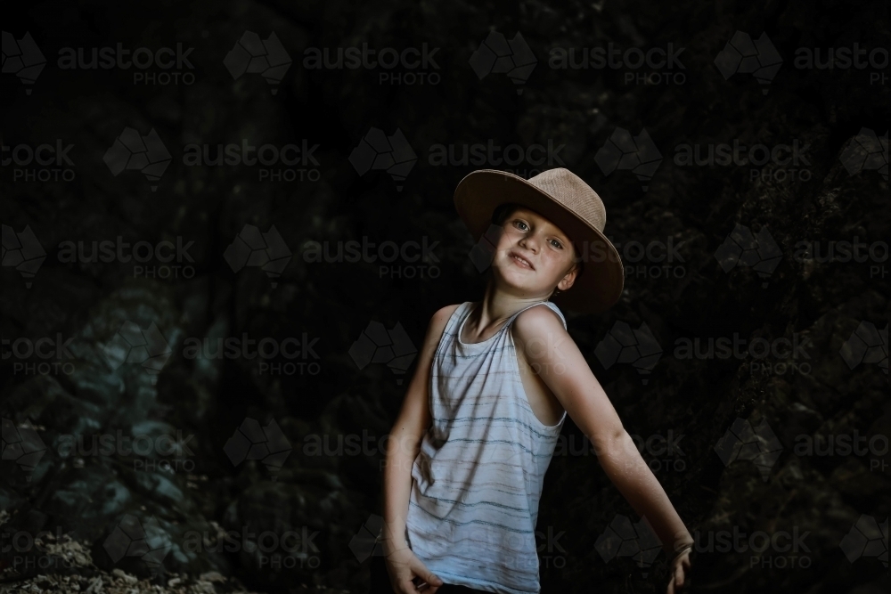 Image of Moody image of young boy exploring dark cave in tropical north ...