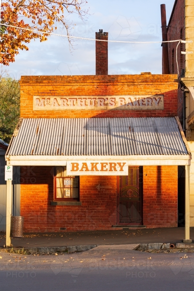 Image of Morning sunshine on the front of a small brick bakery shop ...