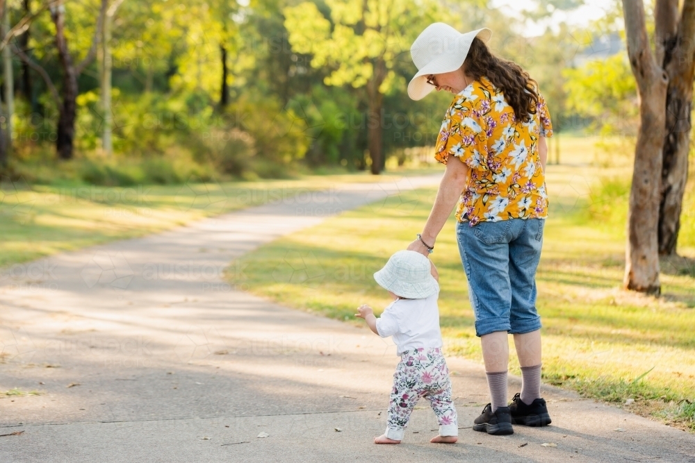 Image of Mother and baby girl walking down footpath in parkland in ...