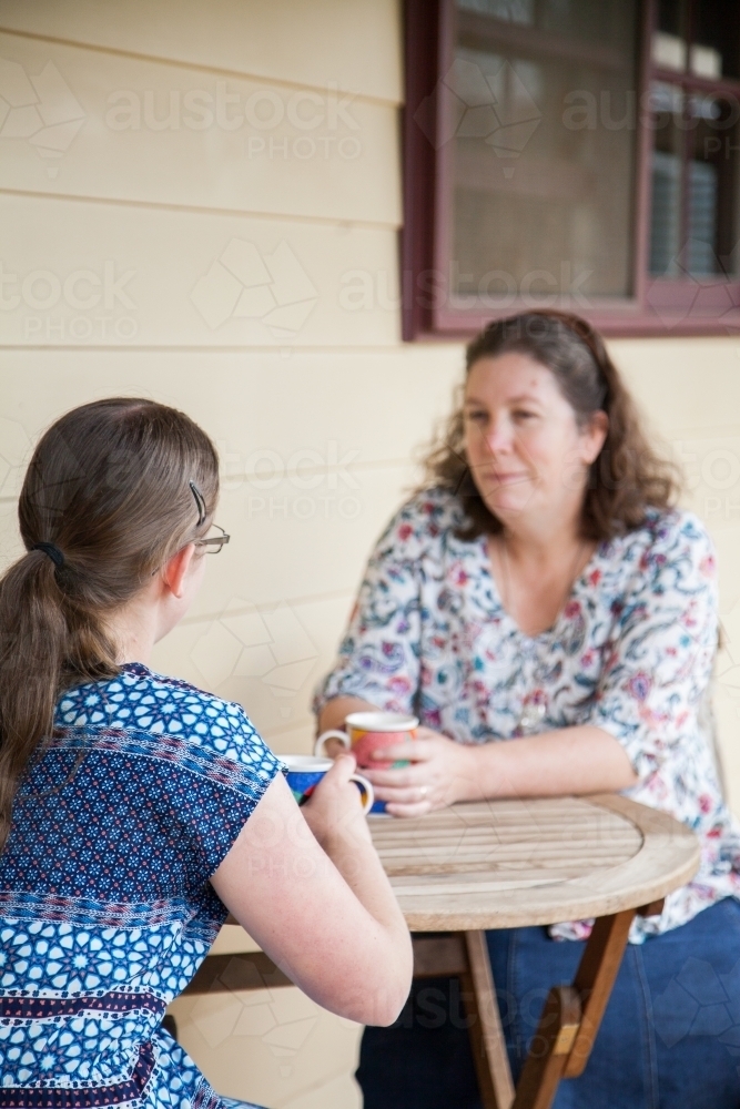 Image of Mother and daughter sitting together talking - Austockphoto