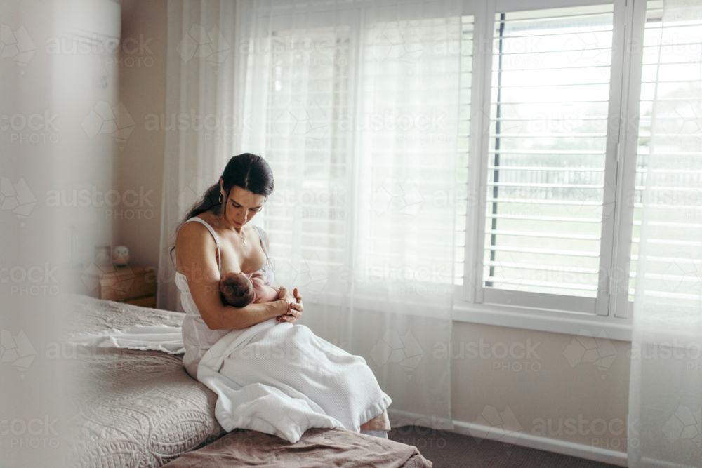 Image of Mother breastfeeding newborn baby in the bedroom. - Austockphoto