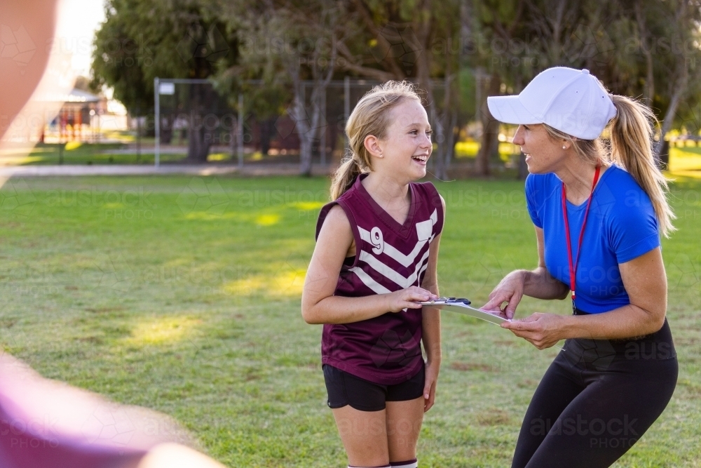 Image of mother coaching her daughter at football - Austockphoto
