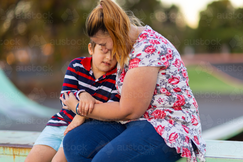 Image of mother comforting her child as they sit together in a park ...