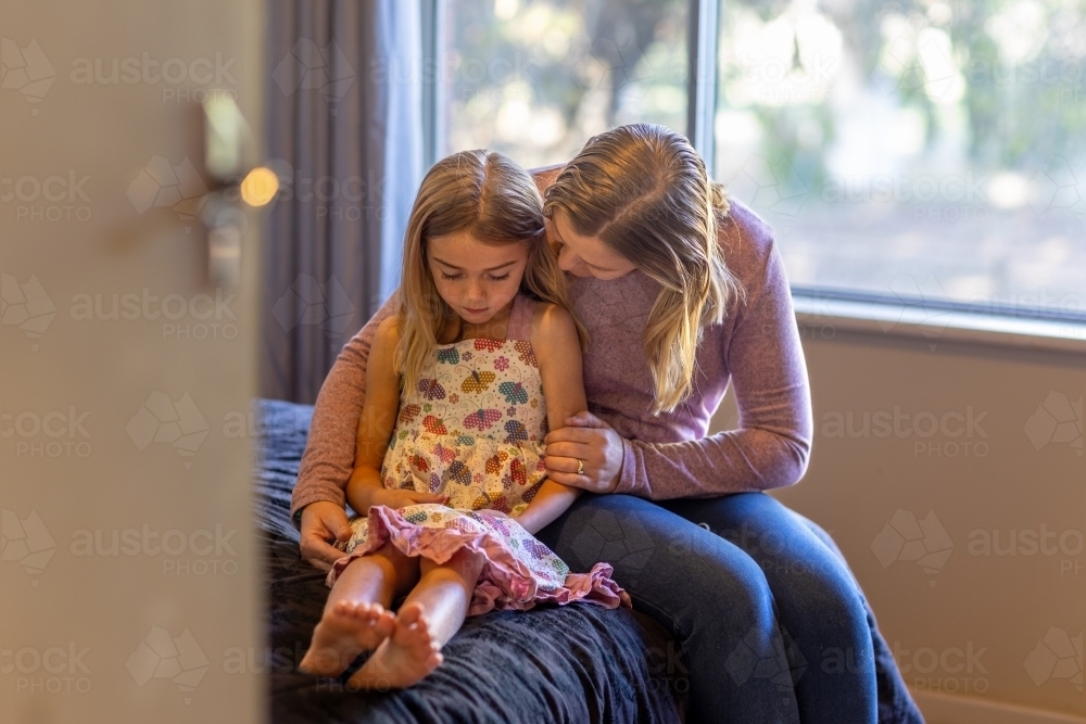 Image of mother comforting her child in bedroom seen through open door ...
