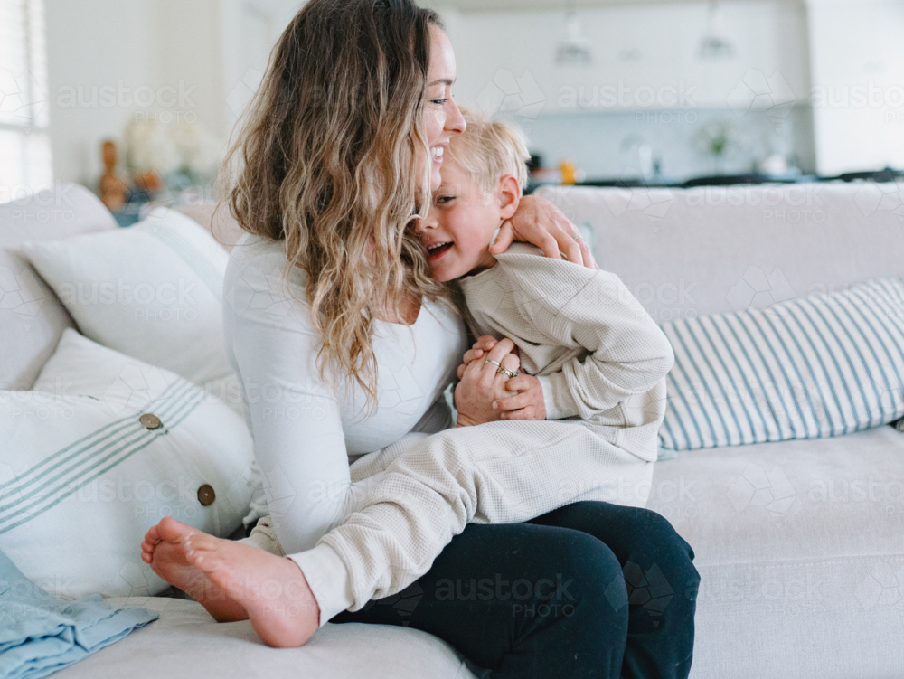 Image of Mother cradles son on her lap in an embrace - Austockphoto