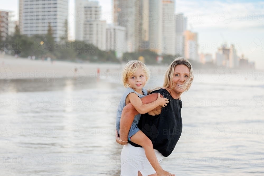 Image of Mother giving son piggy back ride on Main Beach, Surfers ...